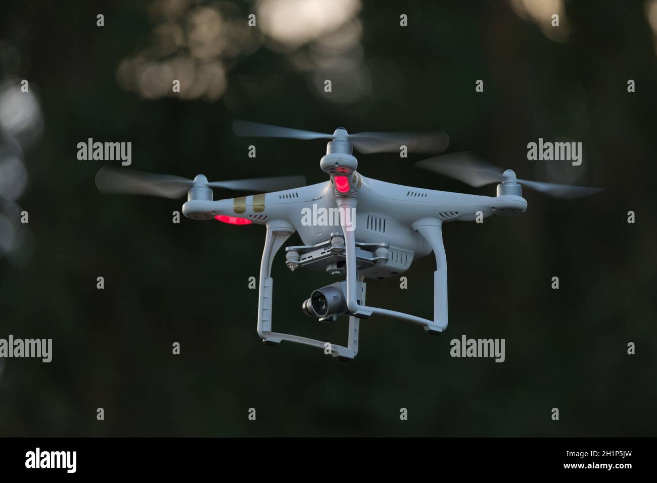 17 - White quad copter drone with red lights on a dark background ...