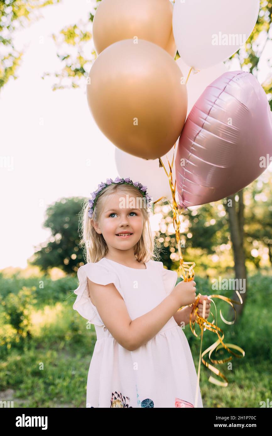Small shiny girl with pink balloons in the garden. High quality photo ...
