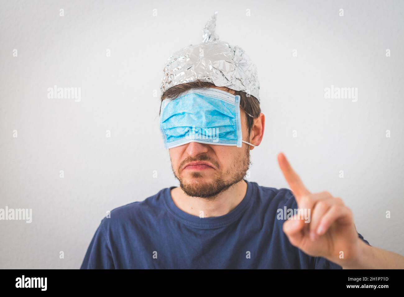 Young angry man with aluminum cap and face mask is gesturing angry ...