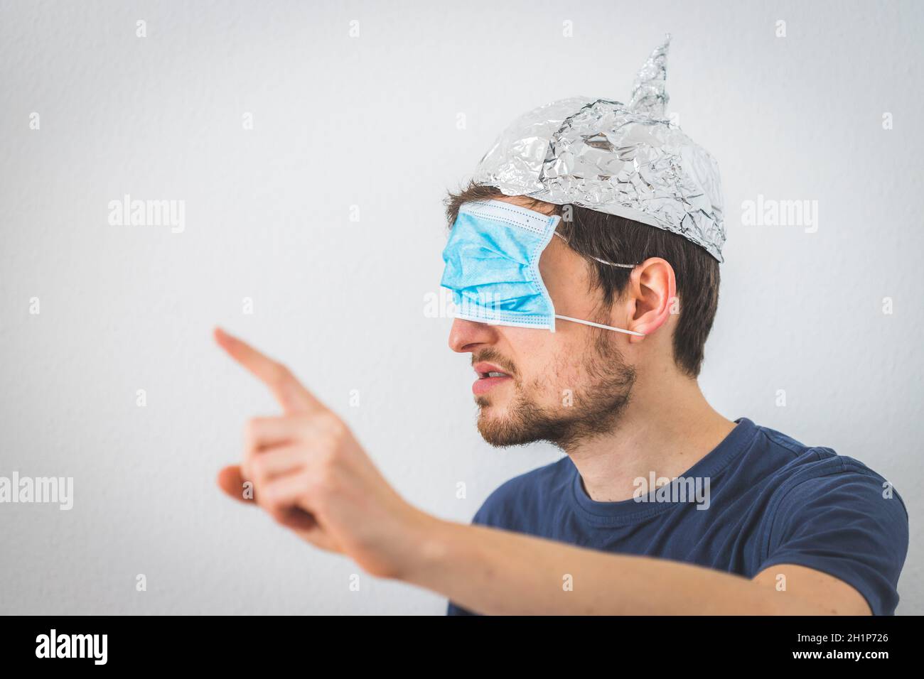 Young angry man with aluminum cap and face mask over the eyes is ...