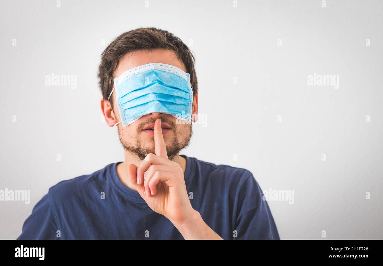 Young angry man with face mask over the eyes is doing a psst! gesture ...