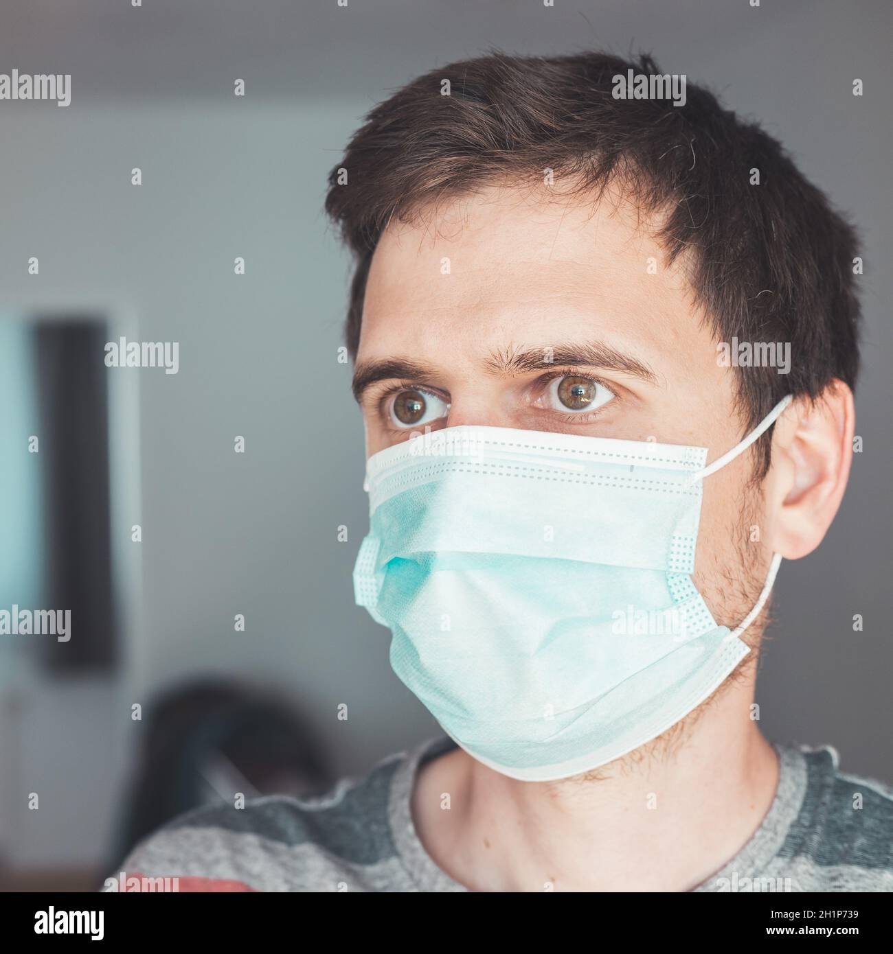 Young man indoor wearing a face mask, portrait. Corona and flu season ...
