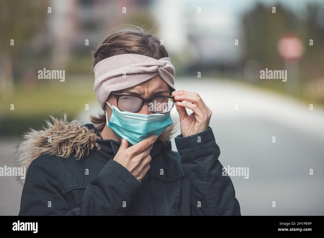 Young woman outdoors wearing a face mask and glasses, tarnished glasses ...