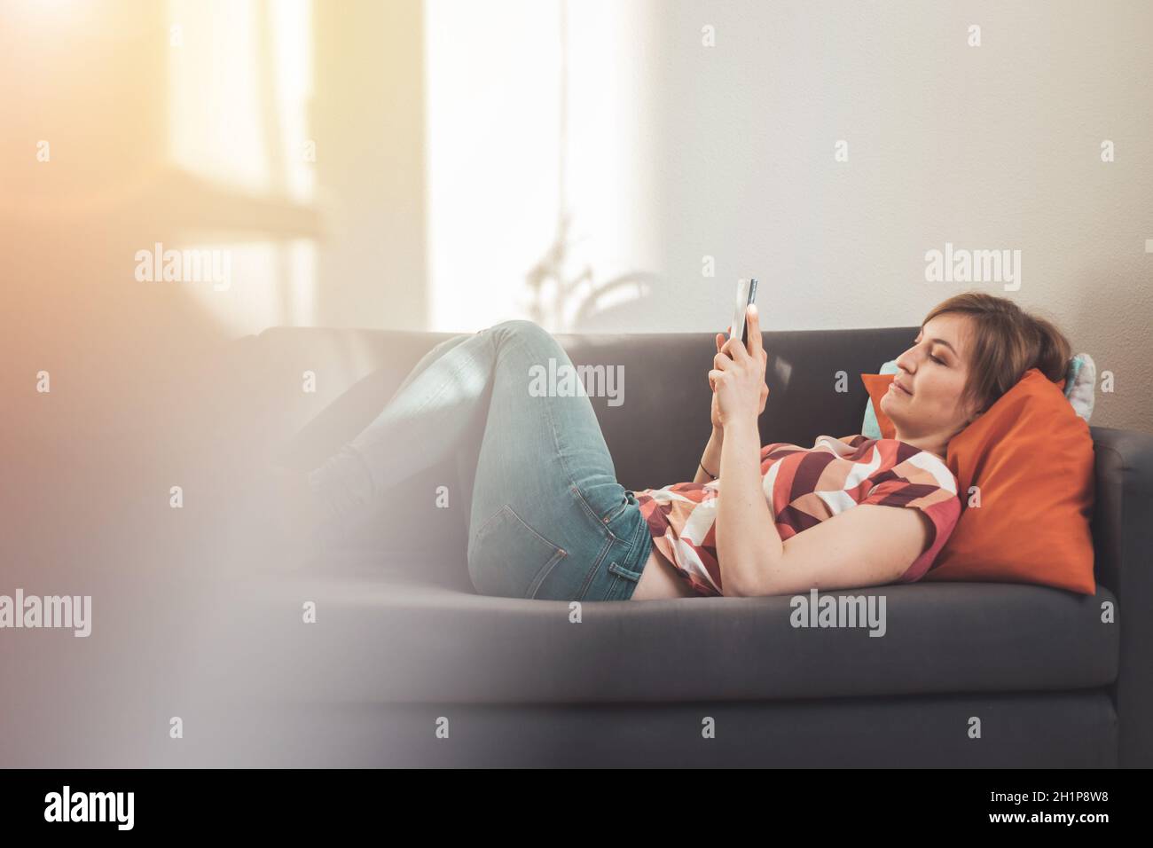 Blond attractive girl is lying on the sofa and texting with her ...