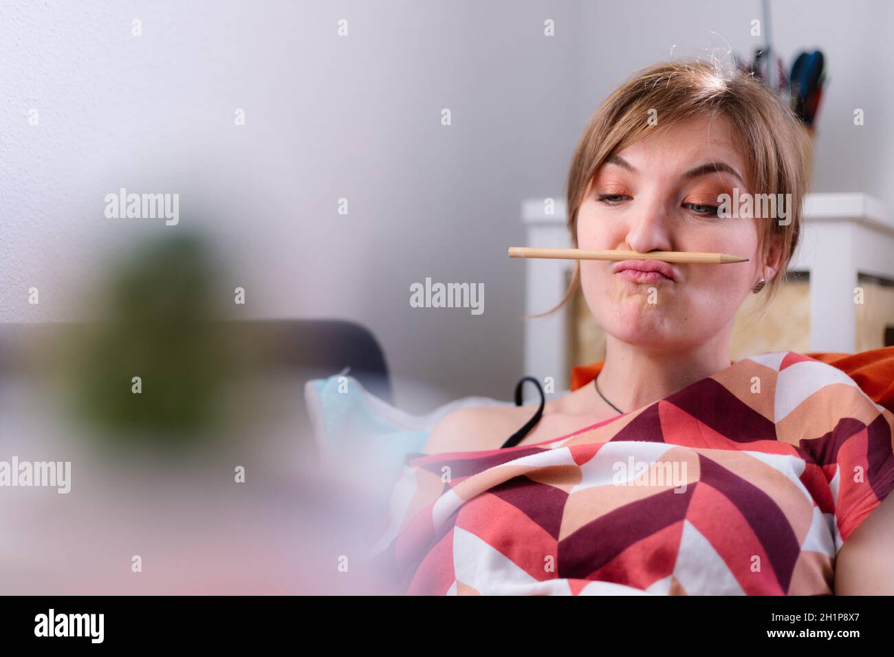 Young Caucasian girl is fooling around and home, pencil trapped between ...