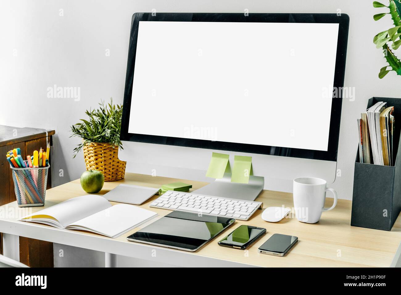Computer monitor with mockup white screen on office table with supplies ...