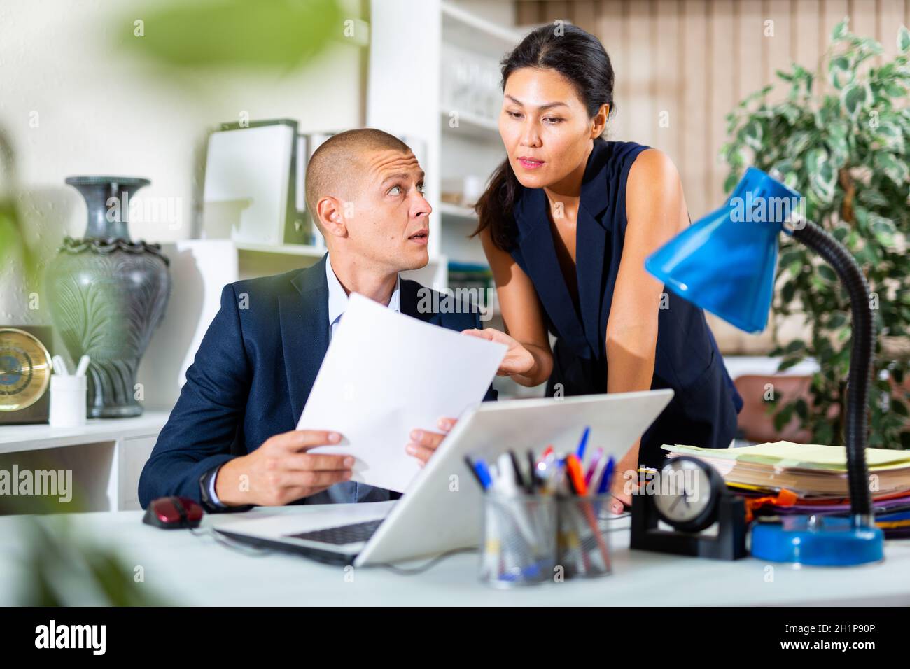 Businessman with female partner working on laptop at office desk Stock ...