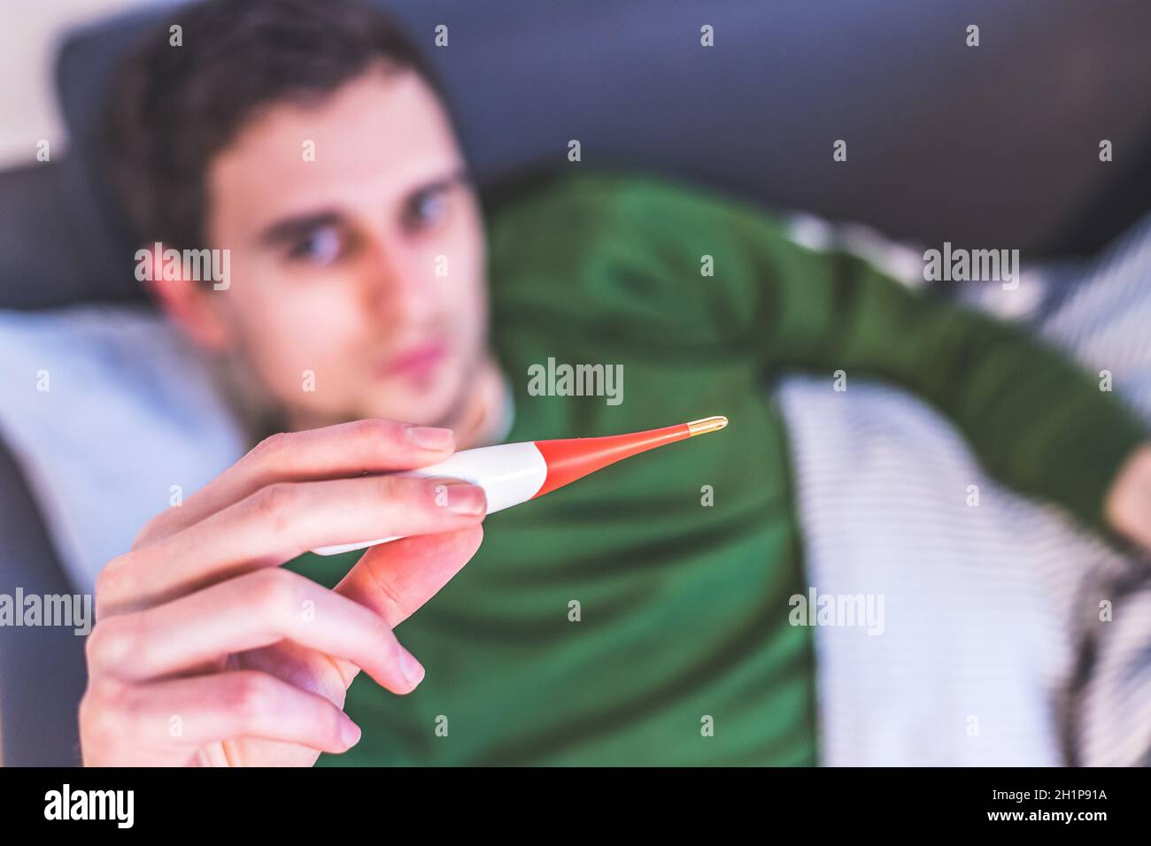 Man is holding a red fever thermometer in his hand Stock Photo - Alamy