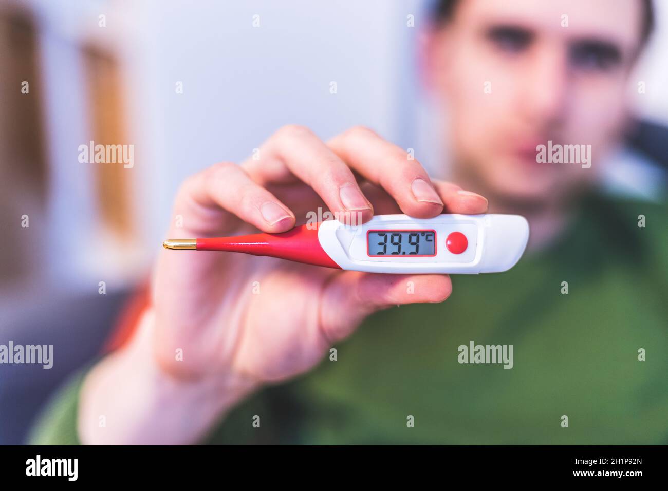 Man is holding a red fever thermometer in his hand Stock Photo - Alamy