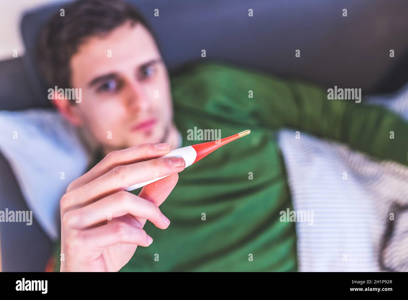 Man is holding a red fever thermometer in his hand Stock Photo - Alamy