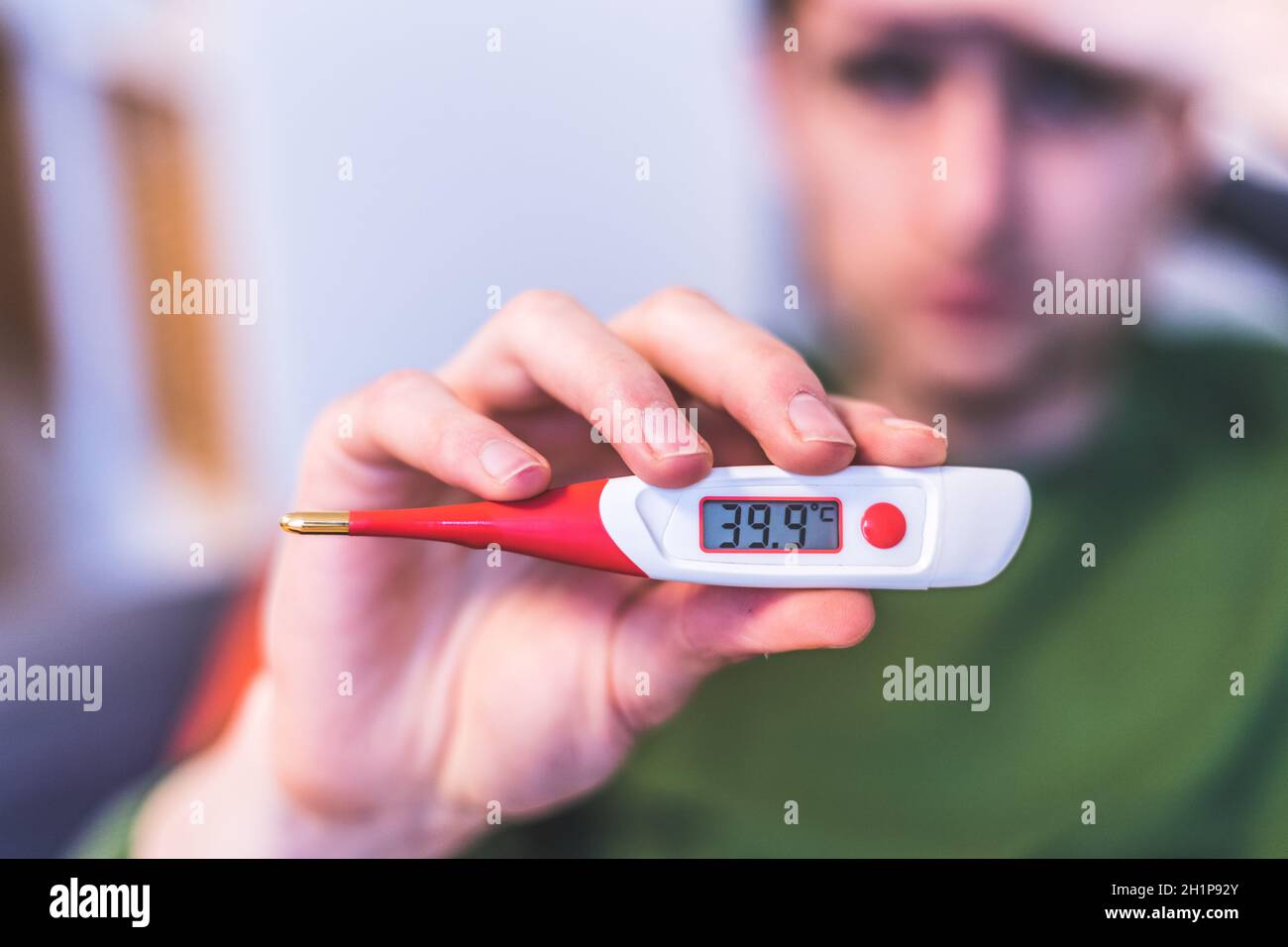 Man is holding a red fever thermometer in his hand Stock Photo - Alamy