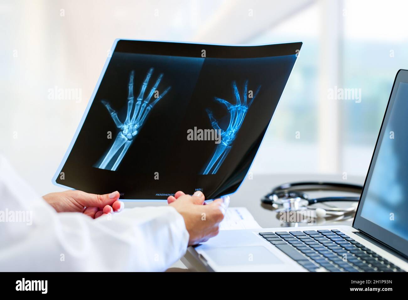 Close up of Female doctor at desk with laptop holding and reviewing ...