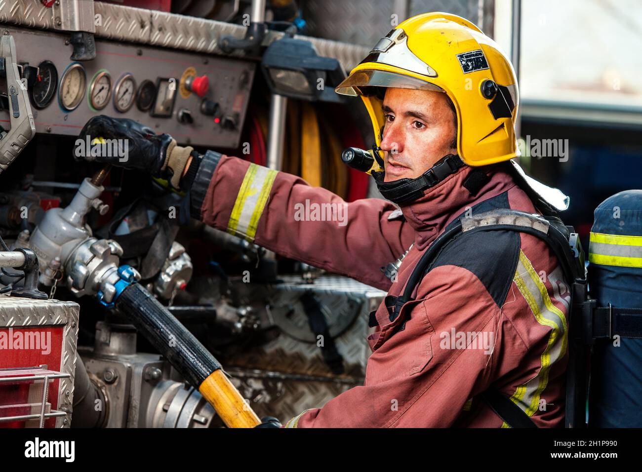 Fireman controlling water pressure at back of fire truck Stock Photo ...