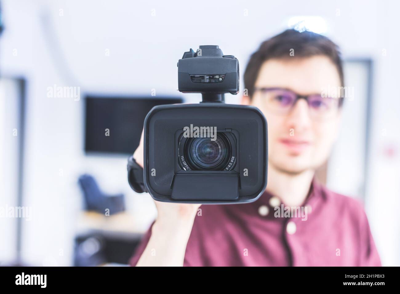 Male cameraman is holding a professional video camcorder, blurry ...