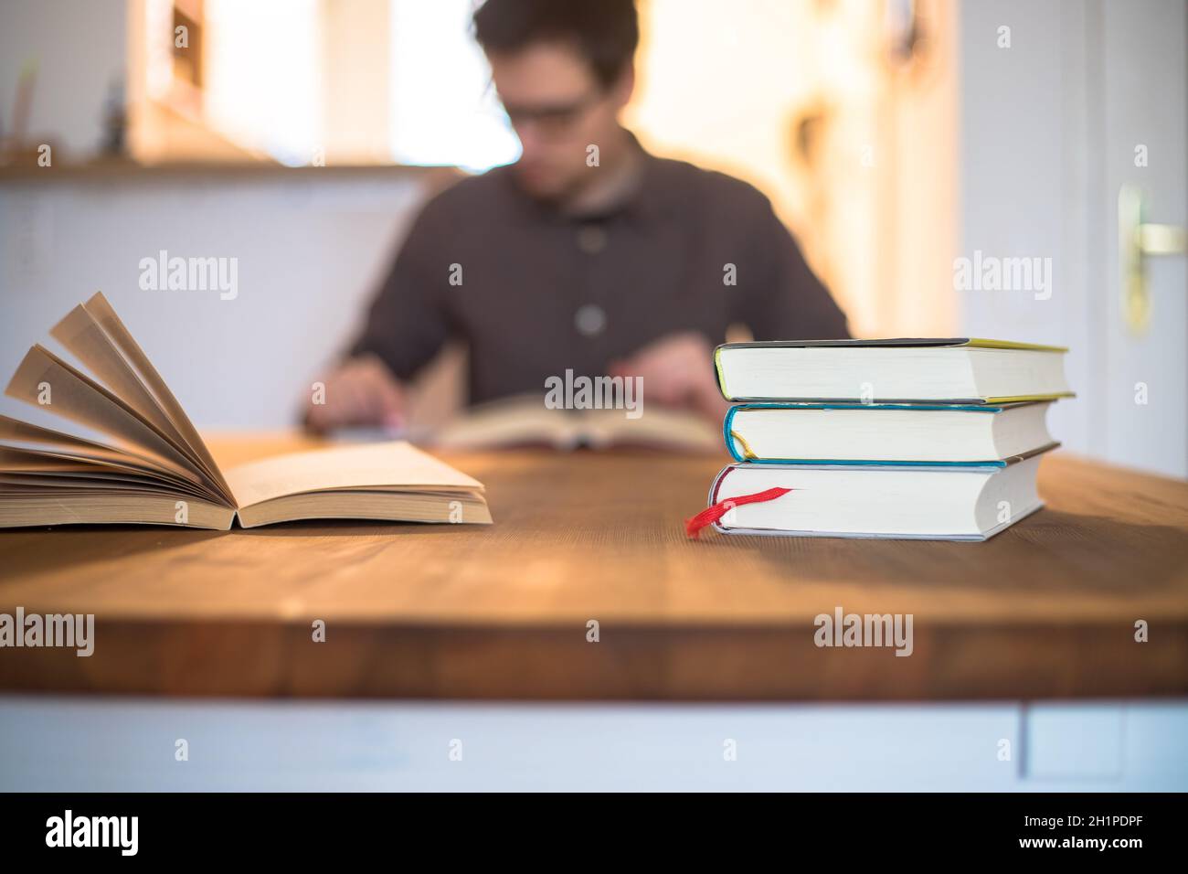 Male student researching and learning at home. Stack of books, person ...