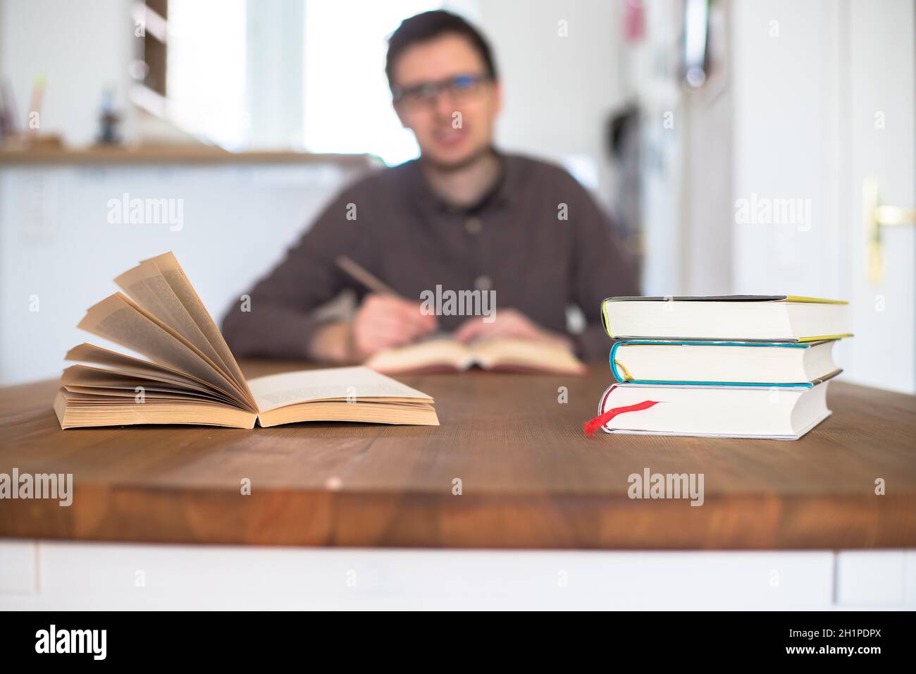 Male student researching and learning at home. Stack of books, person ...