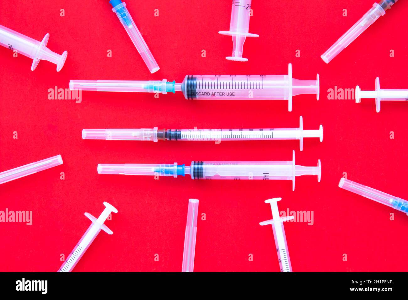 Different syringes injections on a red background Stock Photo - Alamy