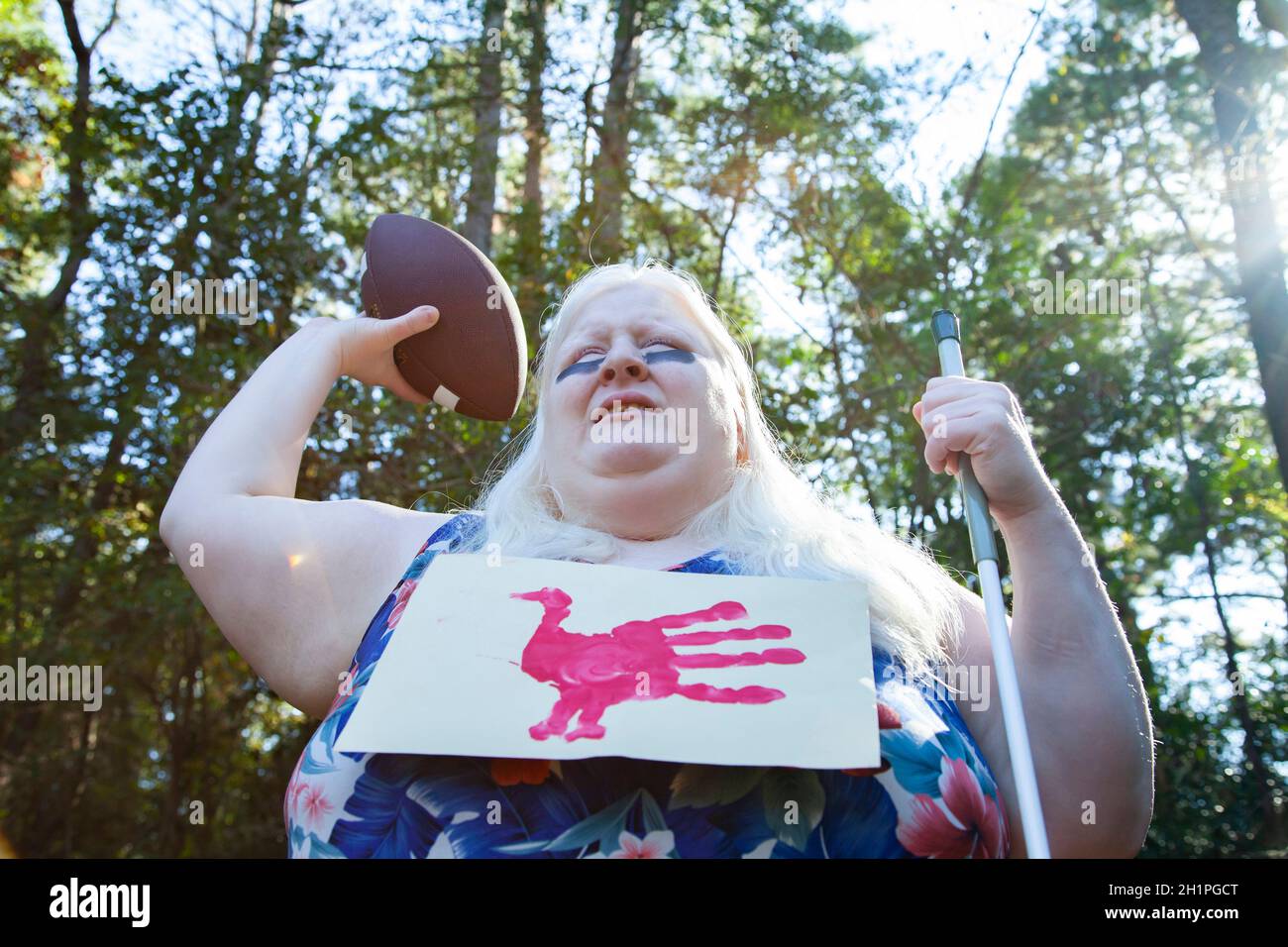 Albino woman wearing a paper hand-turkey napkin, throwing a football ...