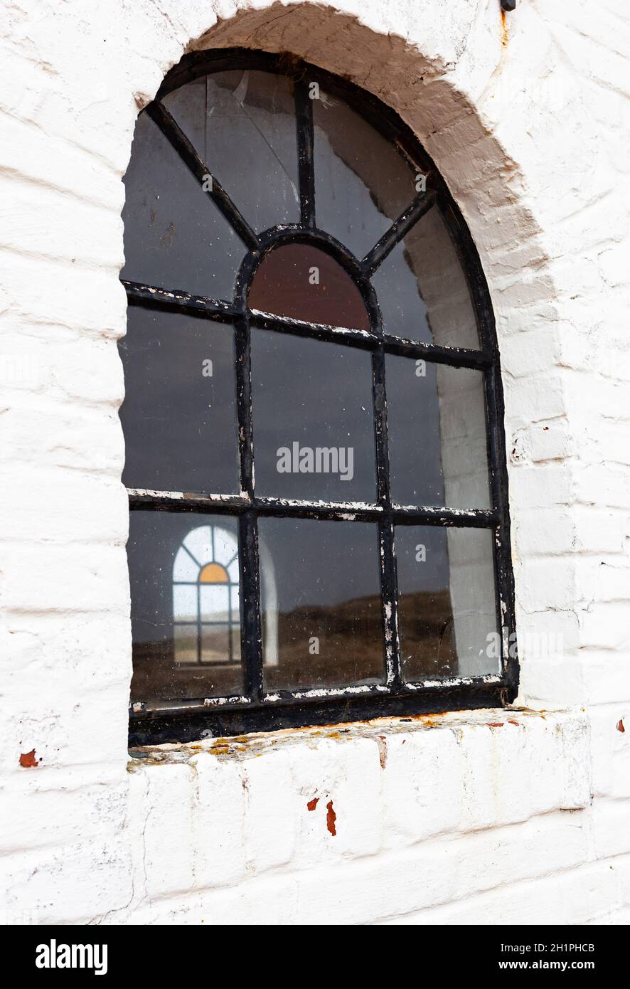 The photo shows an old and weathered barn window with white brick wall ...