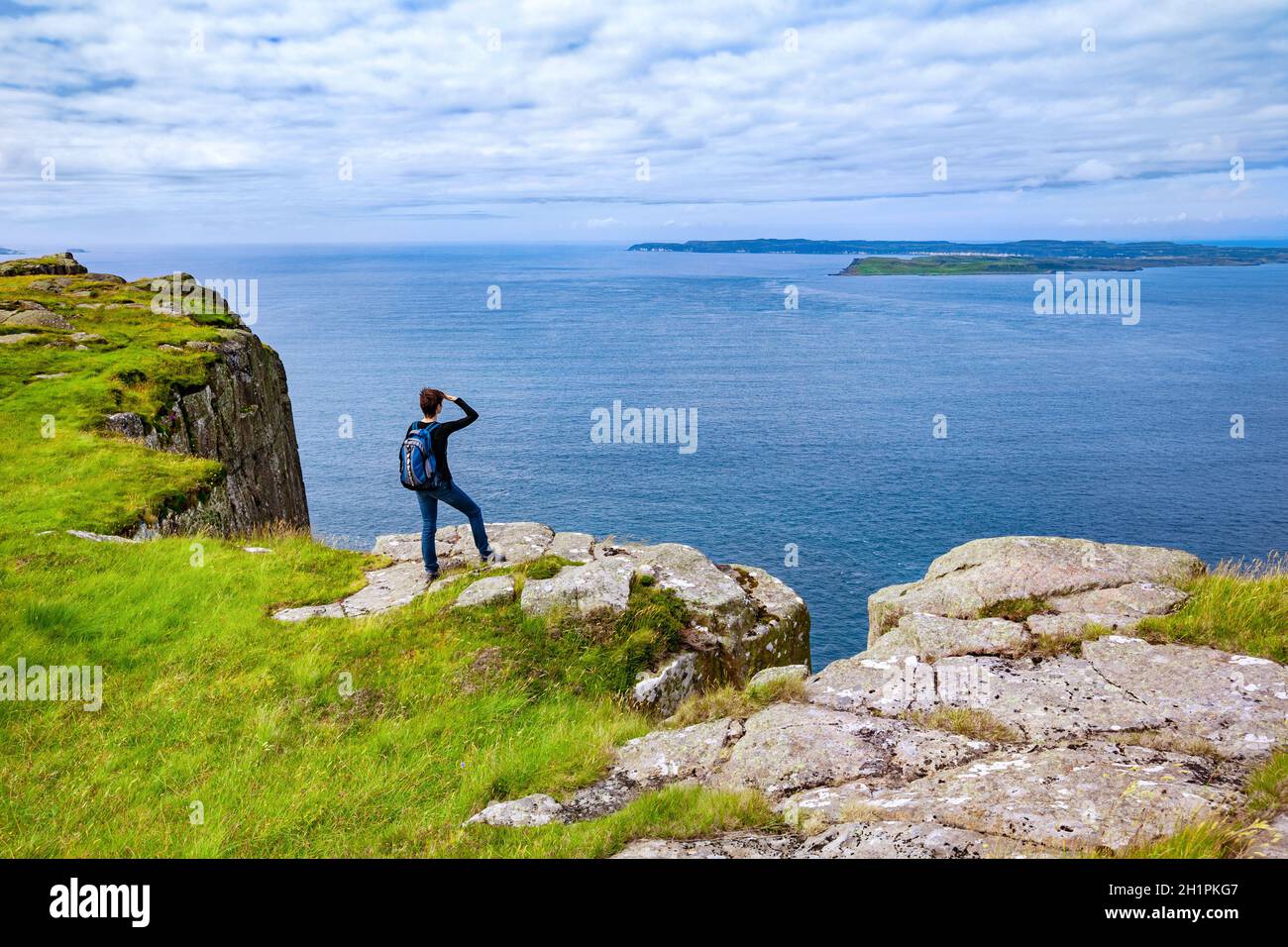 Lonely tourist with backpack standing on the cliff Fair Head and ...
