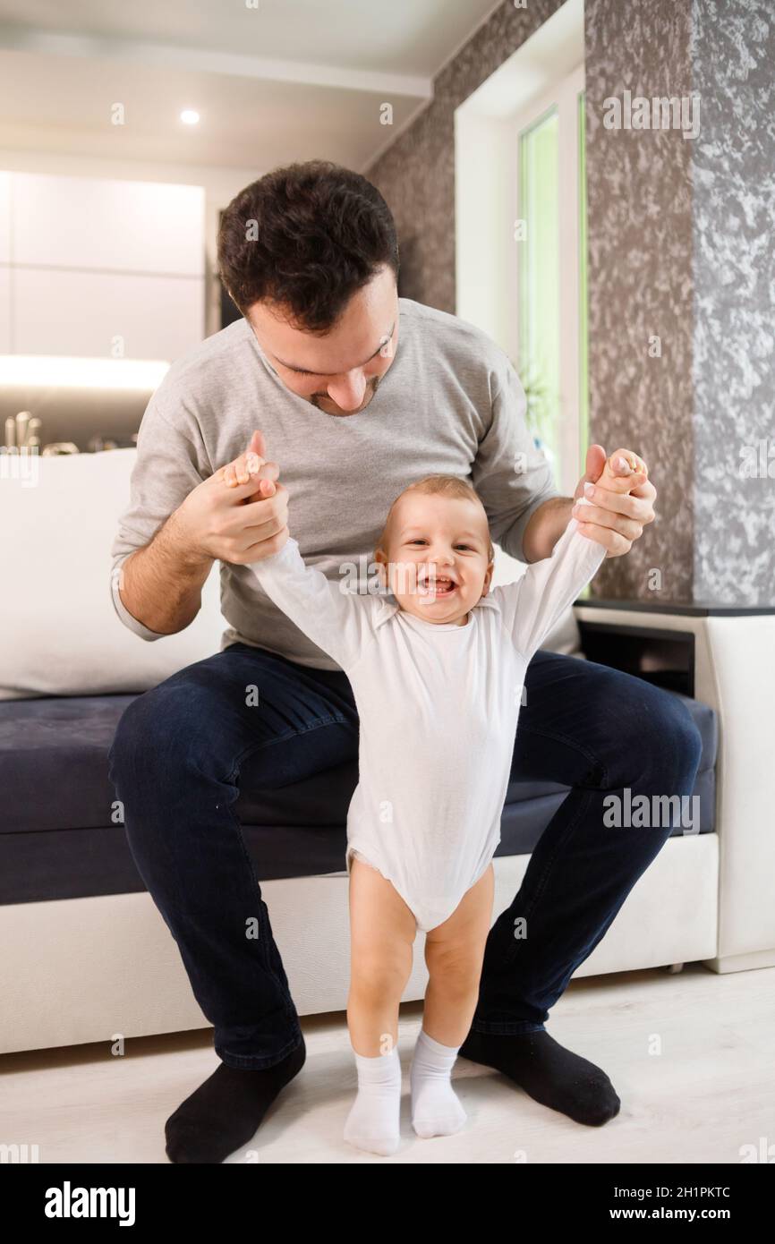 Father teaching a baby to walk in living room at home. First child ...