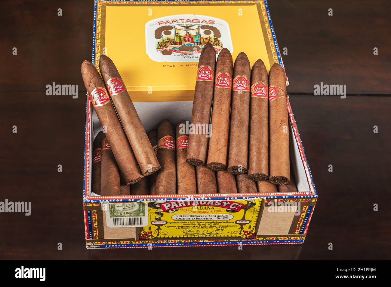 an open box with a lot of partagas cuban cigars inside with red label ...