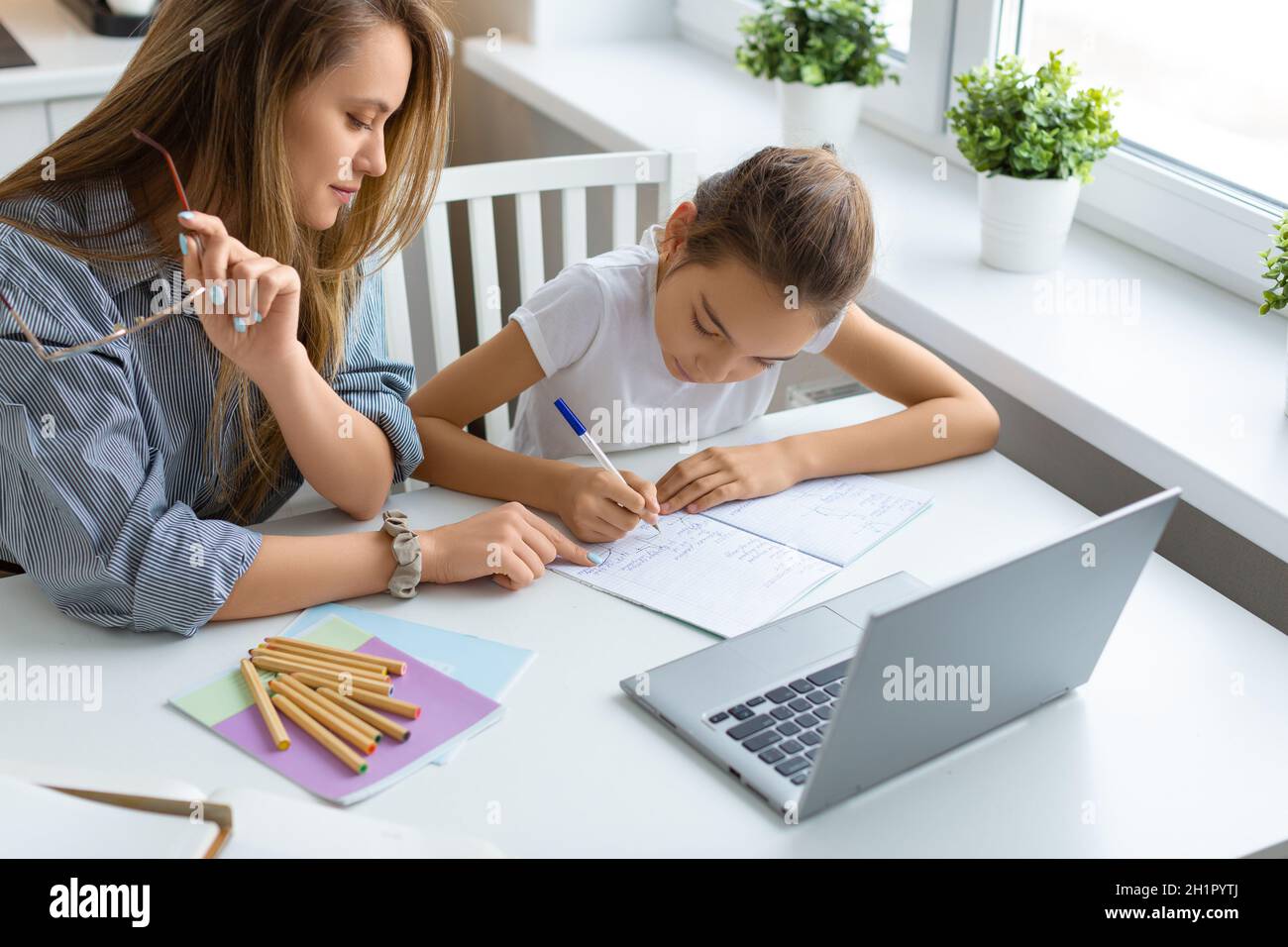 Mom helps her daughter with online homework - family support concept ...