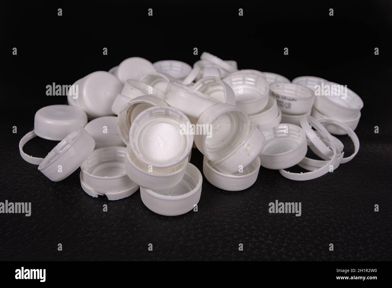 A group of used caps of plastic bottles on a black surface Stock Photo ...