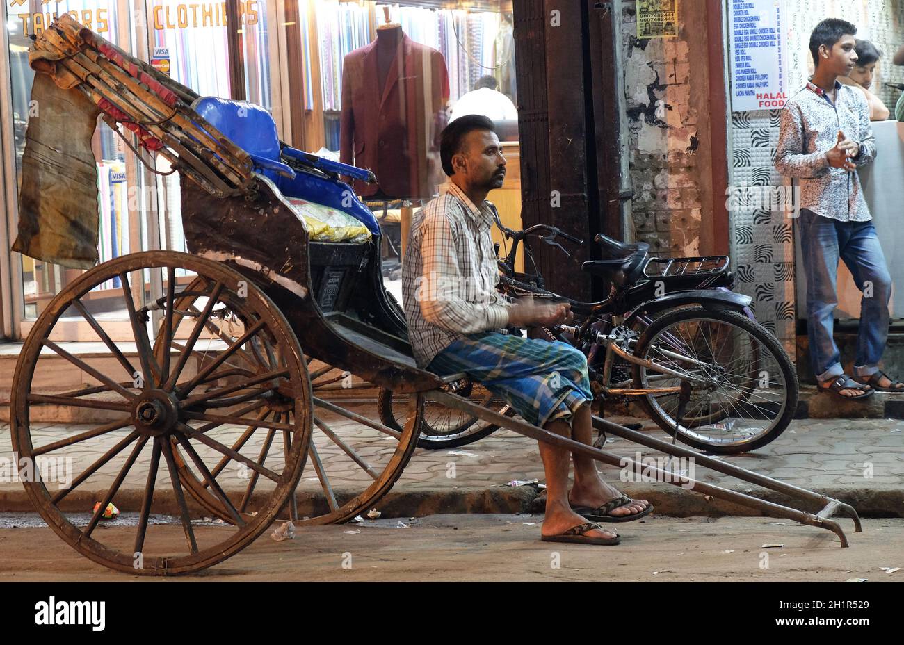 A hand rickshaw puller waits for passengers in his rickshaw in Kolkata ...