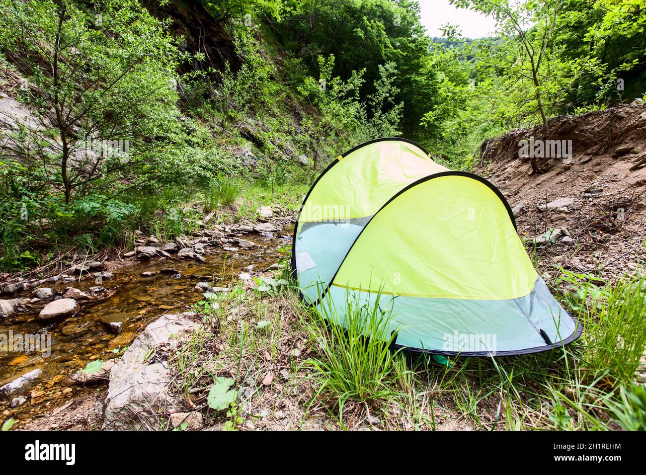 Colorful tourist camping tent near forest stream Stock Photo - Alamy