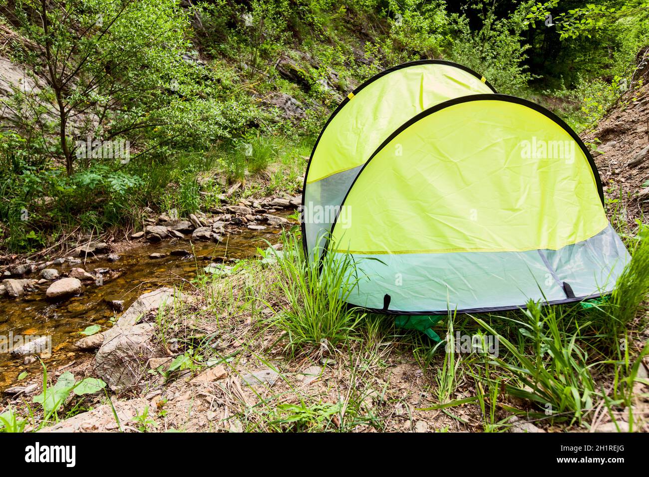 Colorful tourist camping tent near forest stream Stock Photo - Alamy