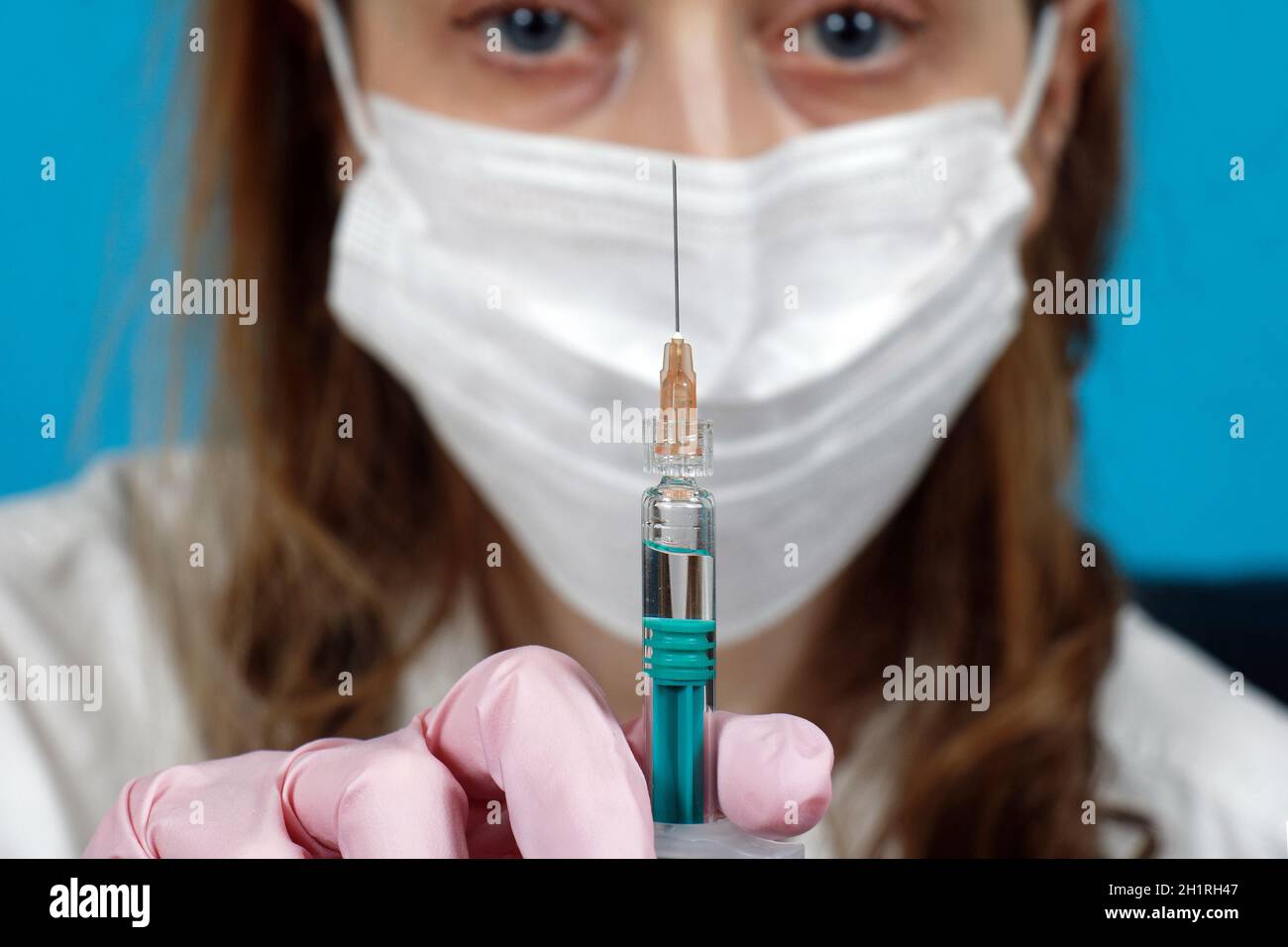 Young medical worker holding full syringe with needle in front of ...