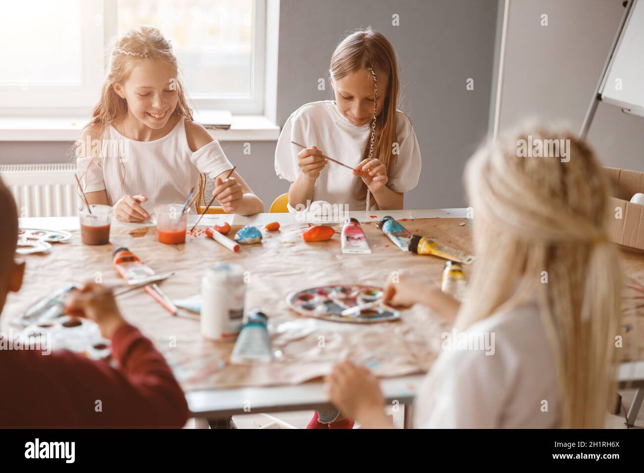 Happy children painting on paper with colorful paints in school Stock ...
