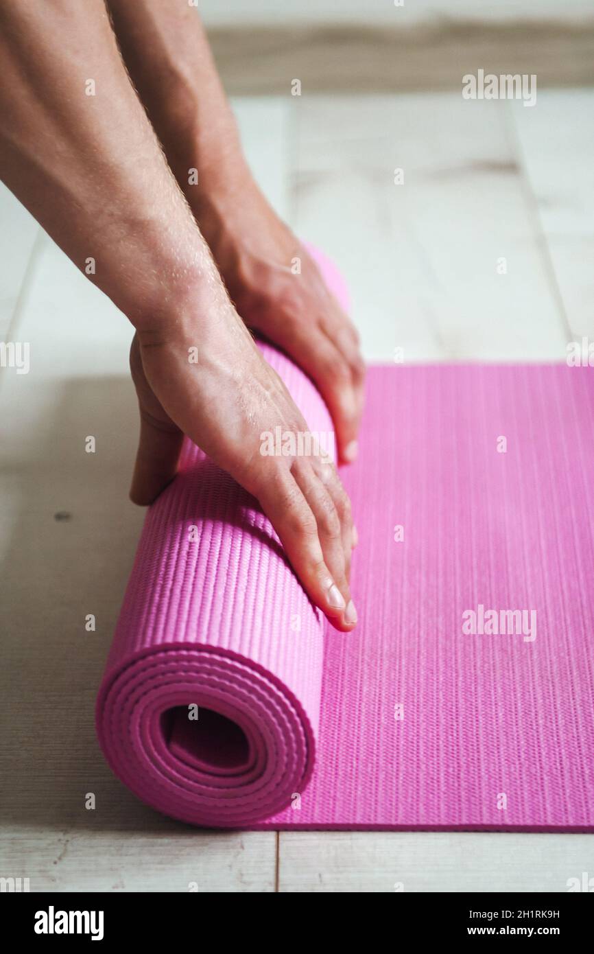 Close-up image of a man's hands unrolling the sports mat preparing to ...