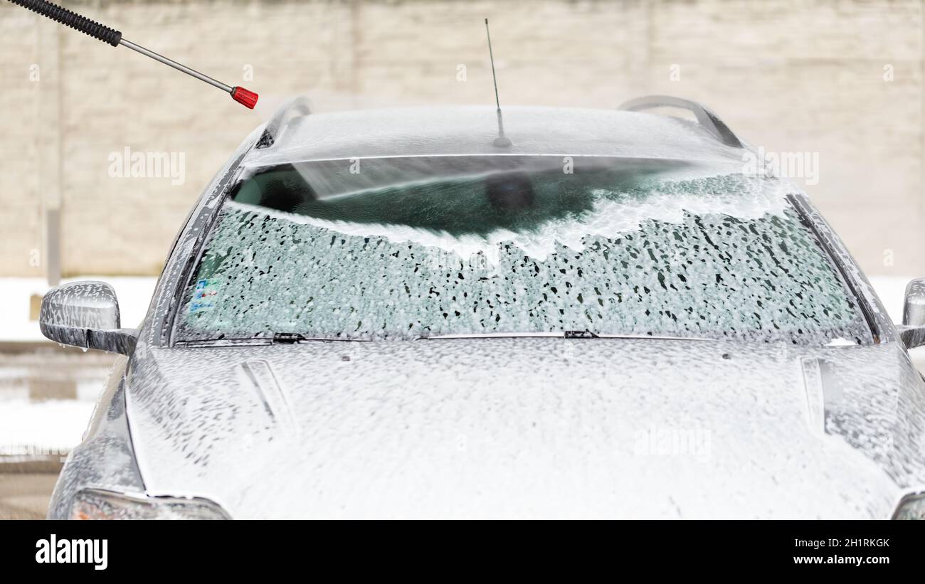 Manual cleaning front of a car with foam and water in carwash Touchless ...