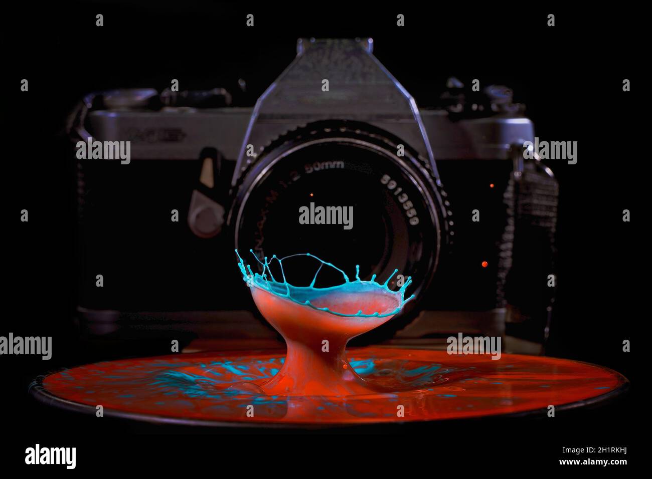 A red and blue water drop collision occurs in front of a camera ...
