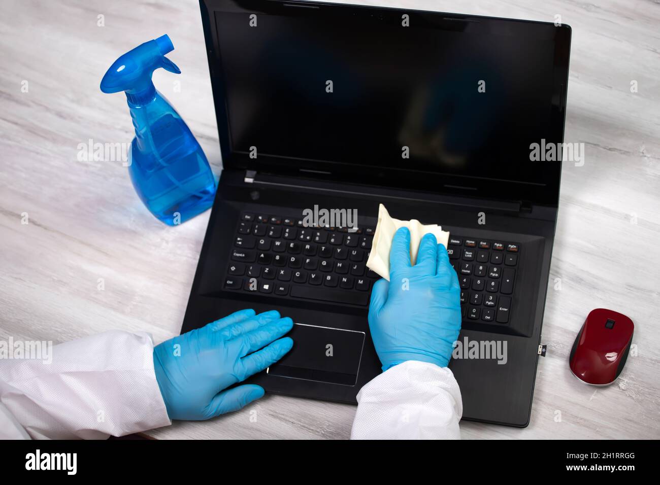 Office sanitizing wiping laptop with disinfectant. Coronavirus COVID-19 ...