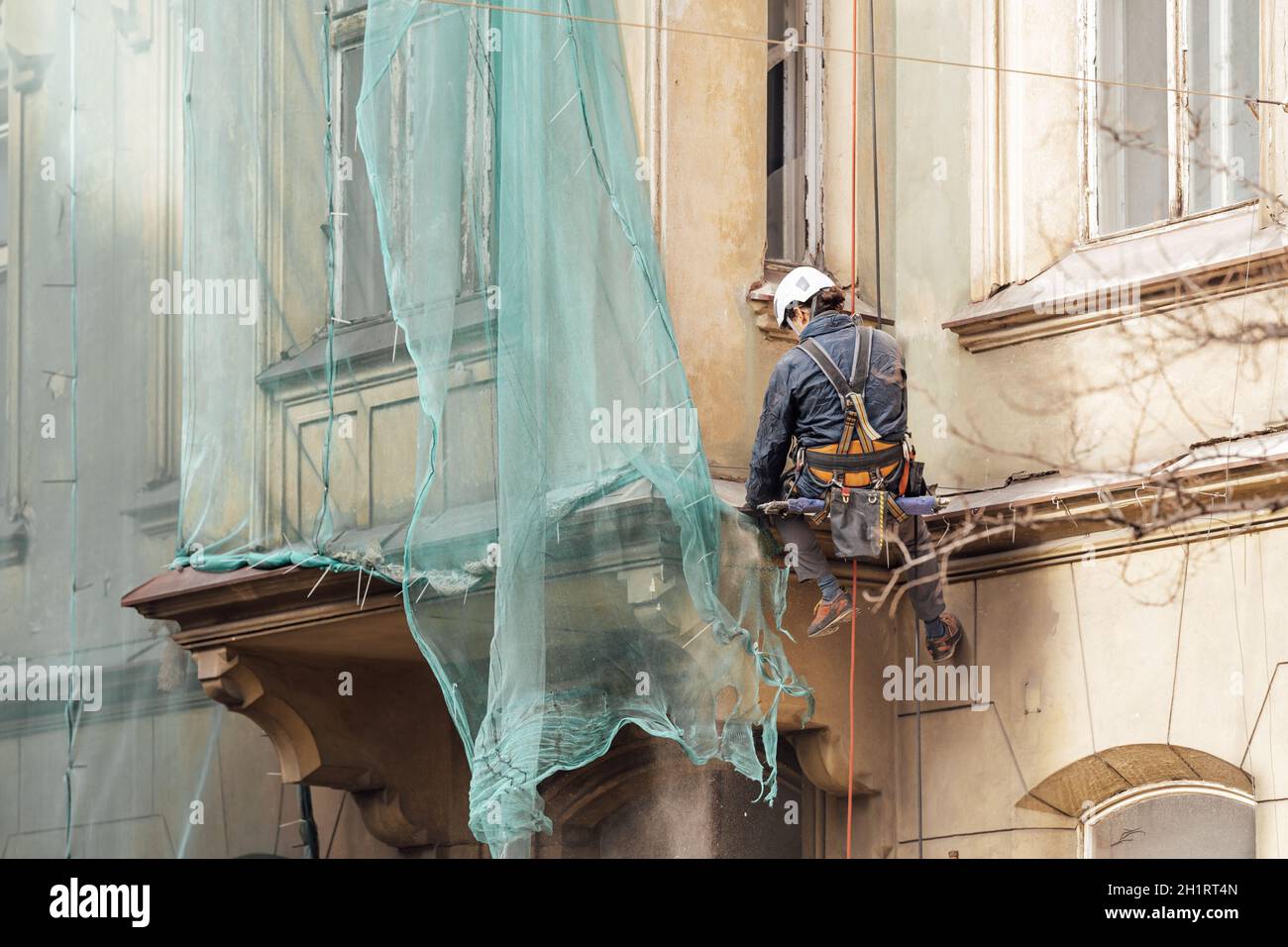 repair of the facade of the house by a man on suspension ropes Stock ...