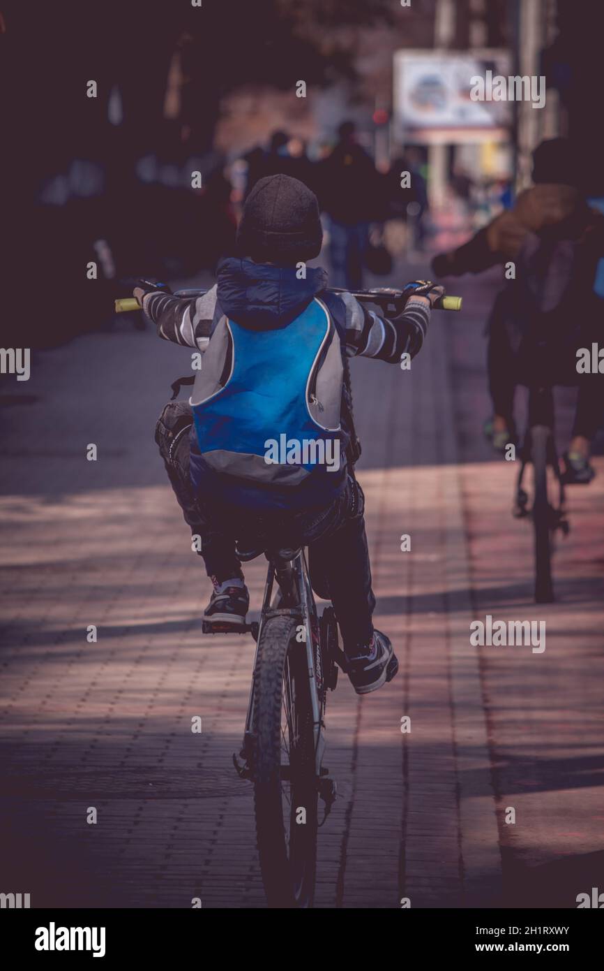Young boy doing a wheelie with his bike on the sidewalk Stock Photo - Alamy