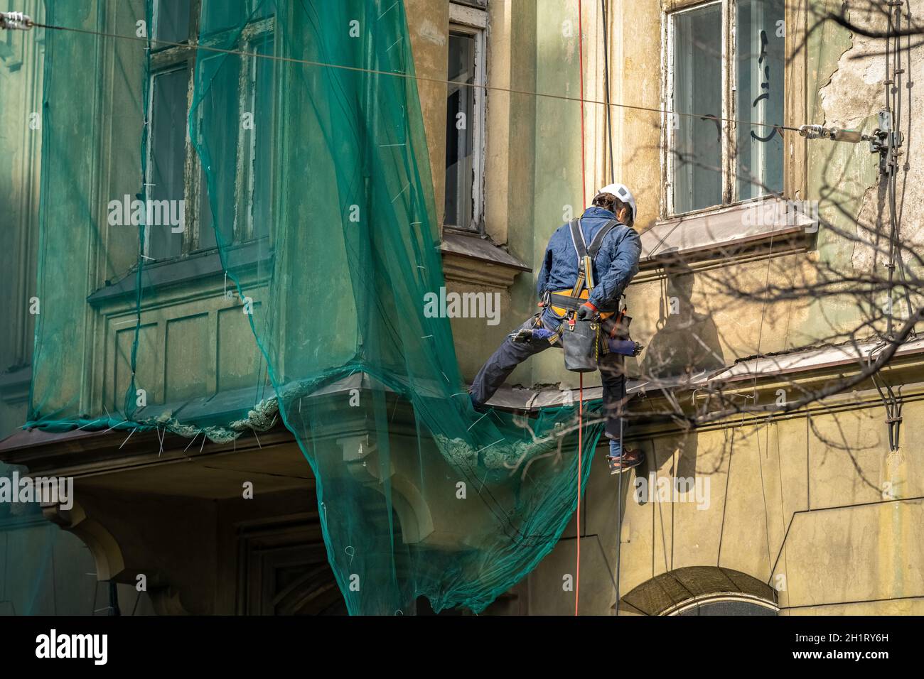 repair of the facade of the house by a man on suspension ropes Stock ...