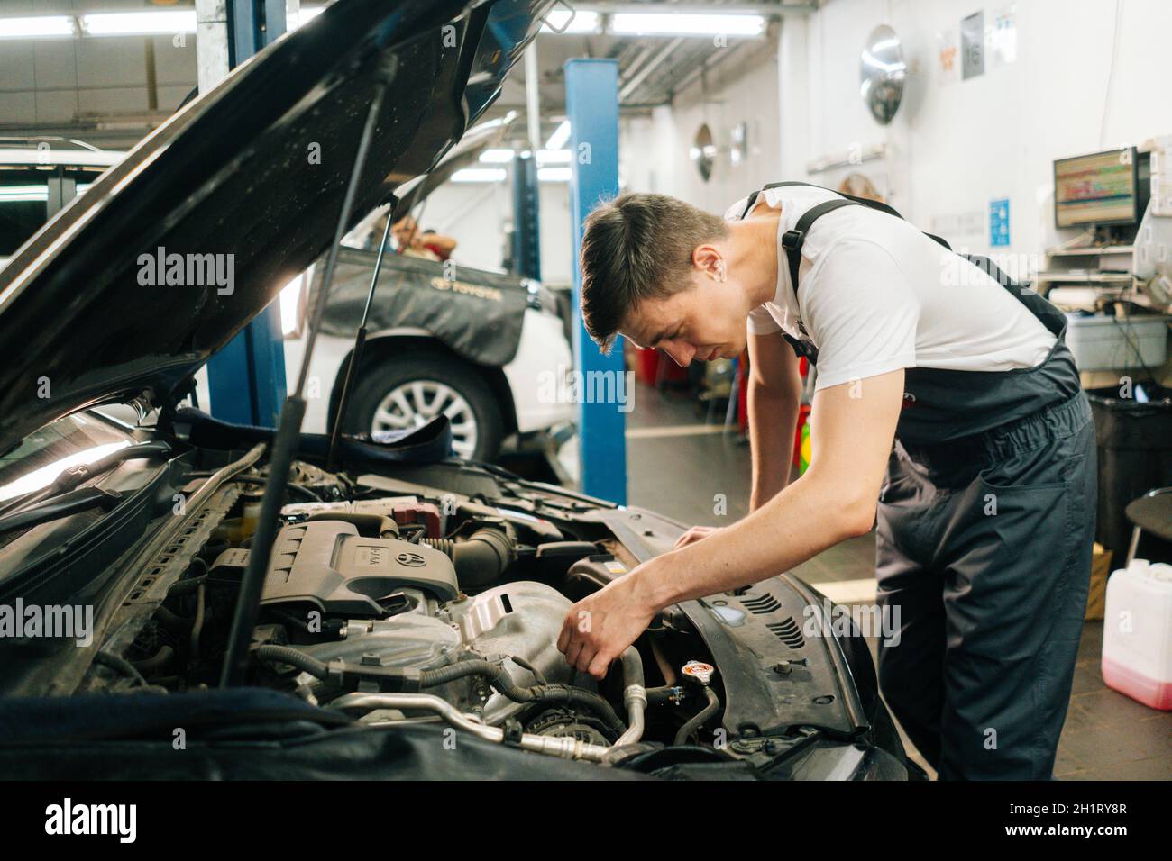 Side view of focused handsome professional male car mechanic in blue ...