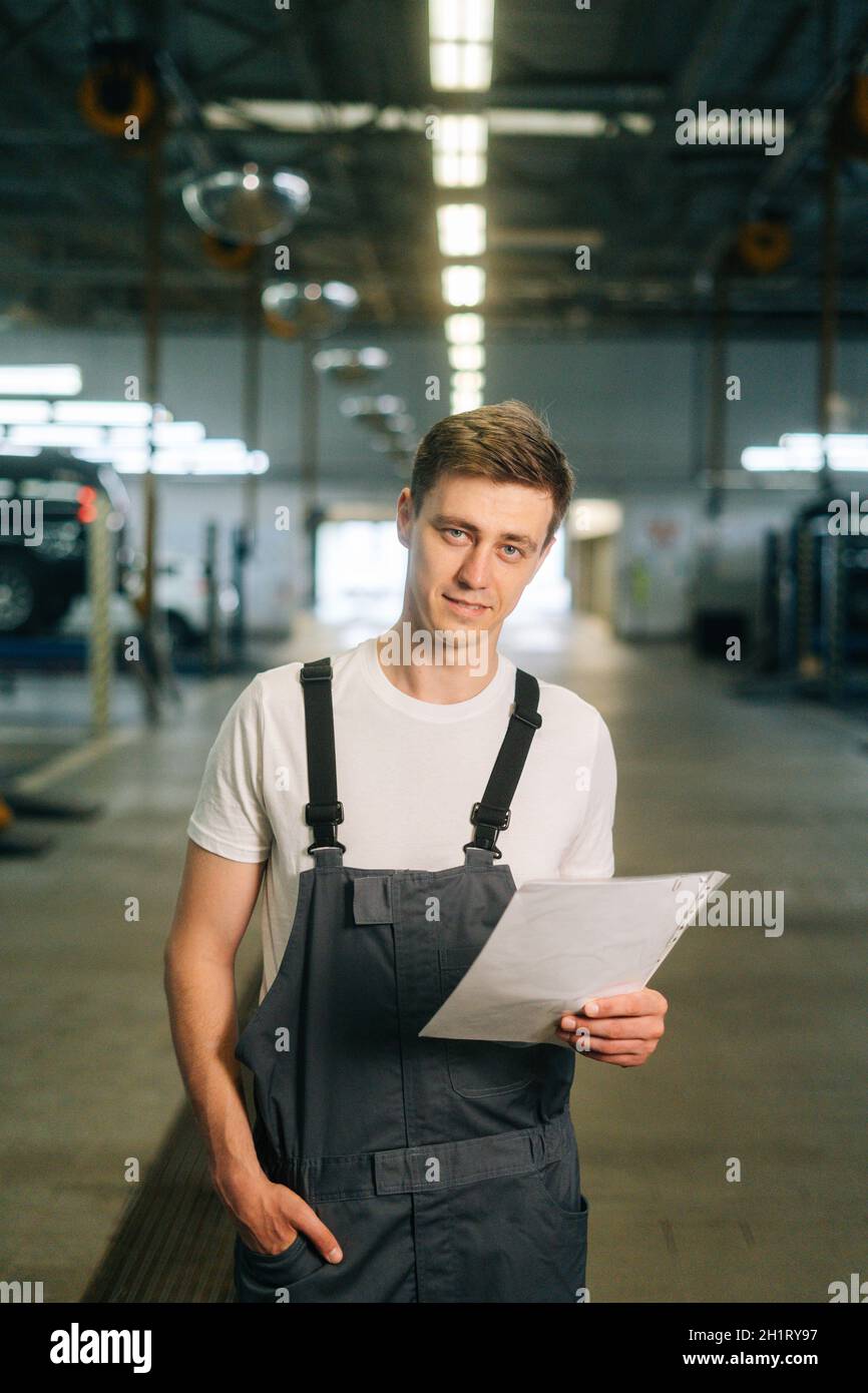 Vertical portrait of confident handsome young mechanic male wearing ...