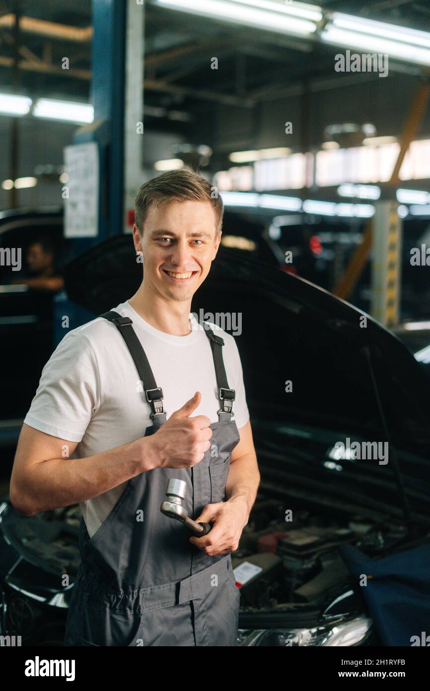 Vertical portrait of smiling handsome young mechanic male wearing ...