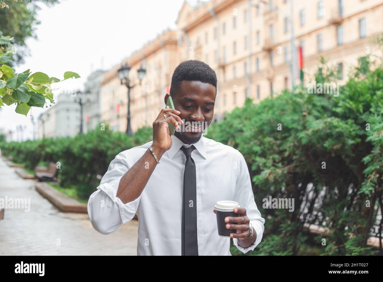 Black american businessman in a rush. Man with takeaway coffee talking ...