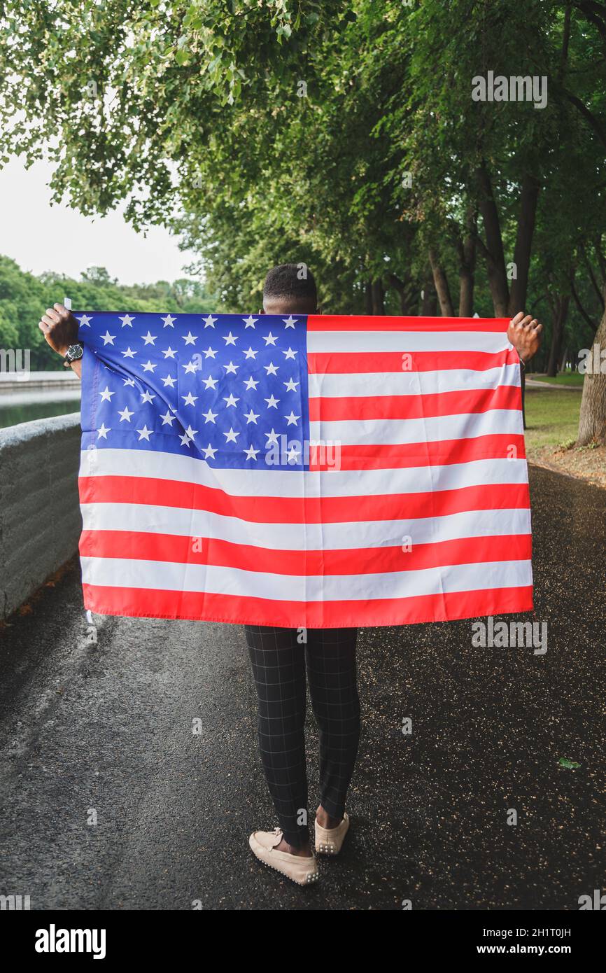 Black african-american man holding USA flag from his back walking ...