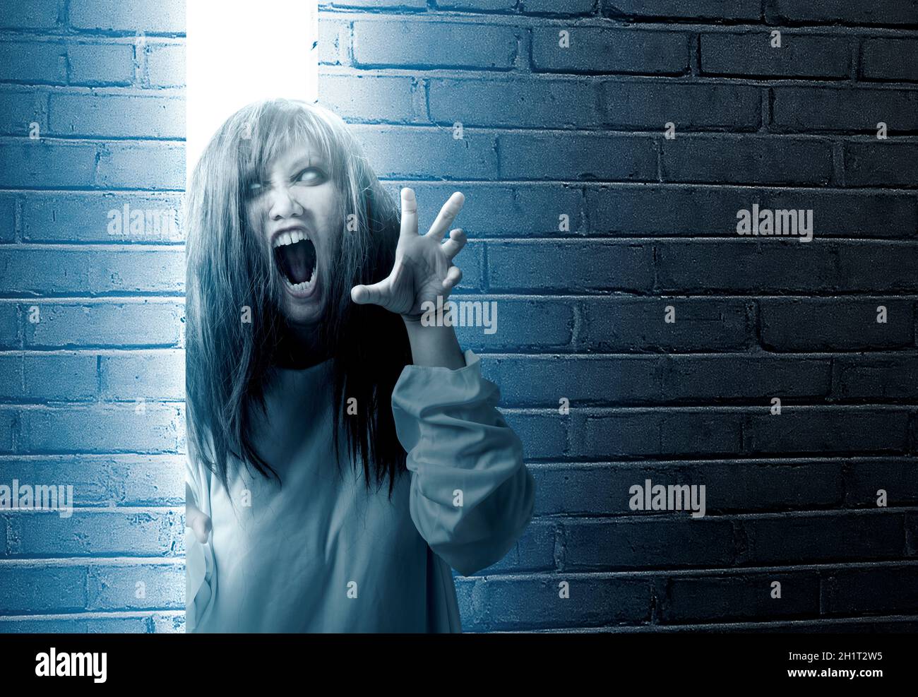 Scary ghost woman standing behind the brick wall with bright background ...