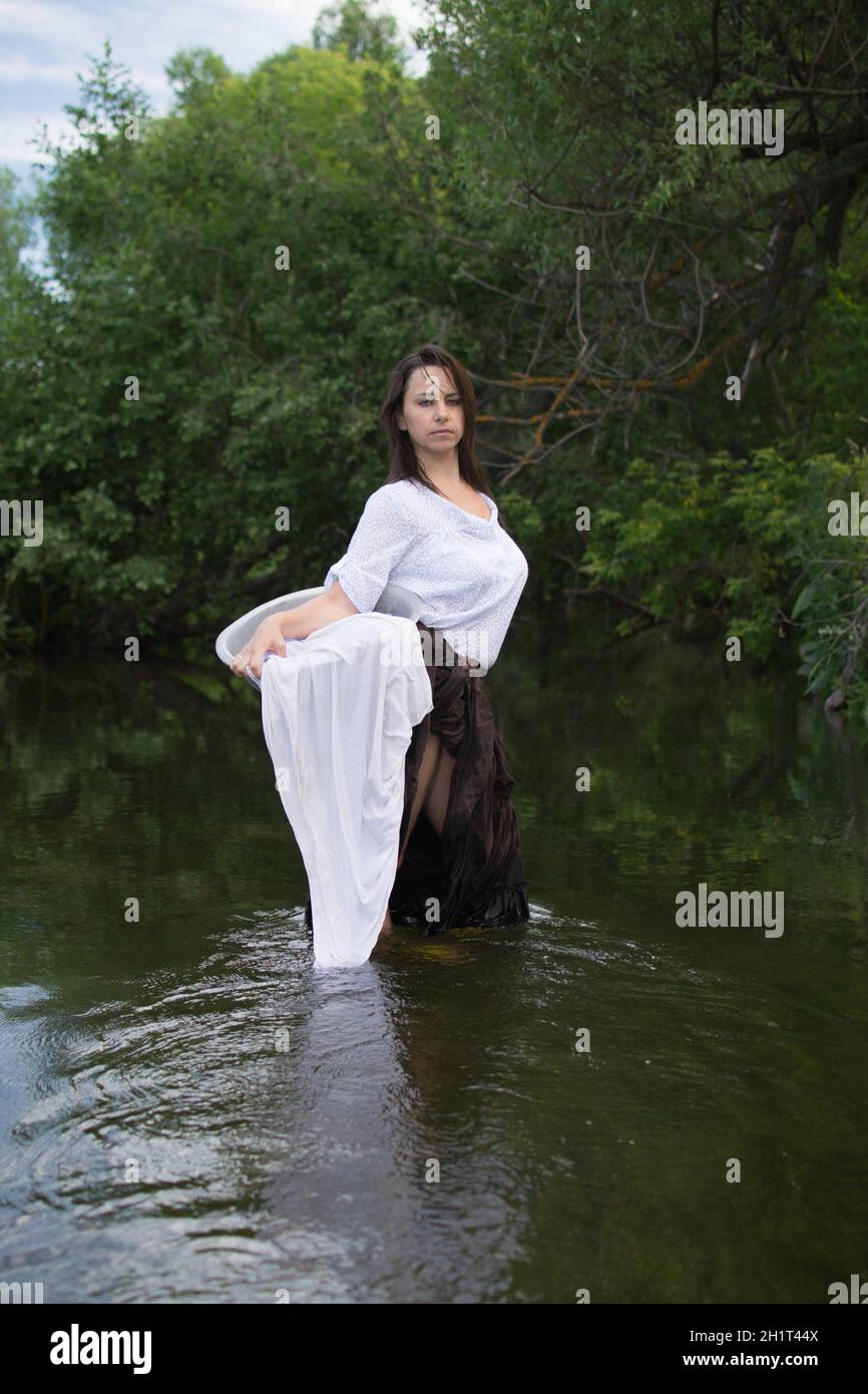 peasant woman washes clothes in the river near the forest Stock Photo ...