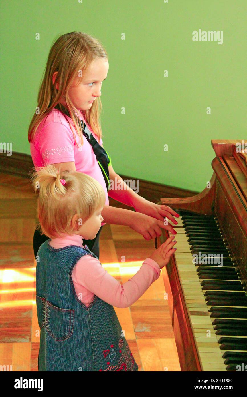 little girls sisters playing piano. Music lessons. Children try to play ...