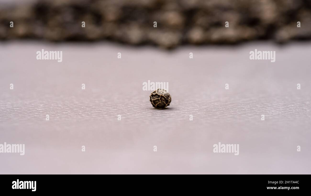 Close up black pepper seeds or peppercorns (macro) in white bowl ...