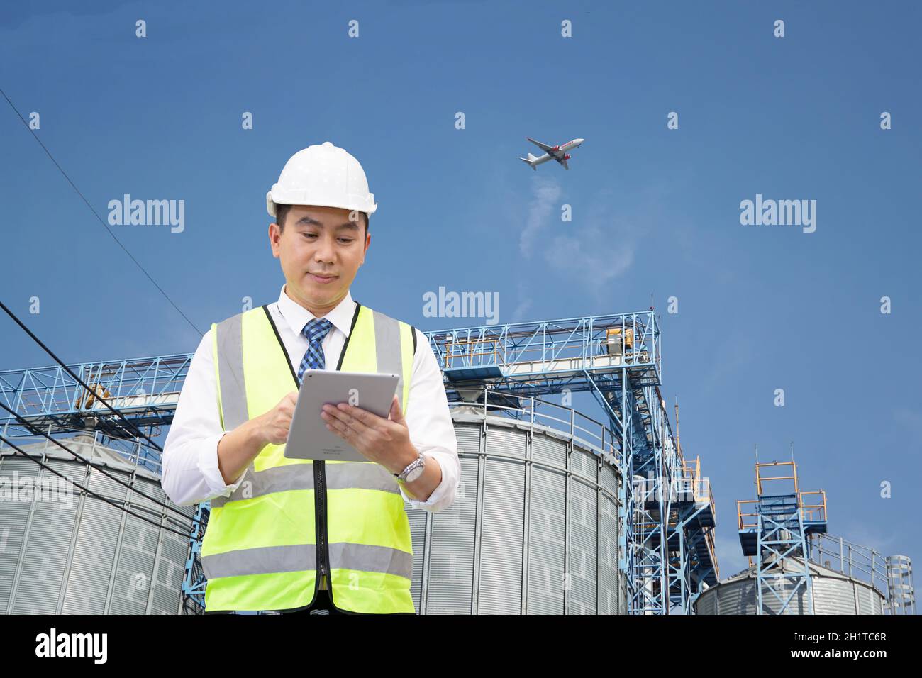 inspection engineer holding tablet computer against fuel tanks at ...